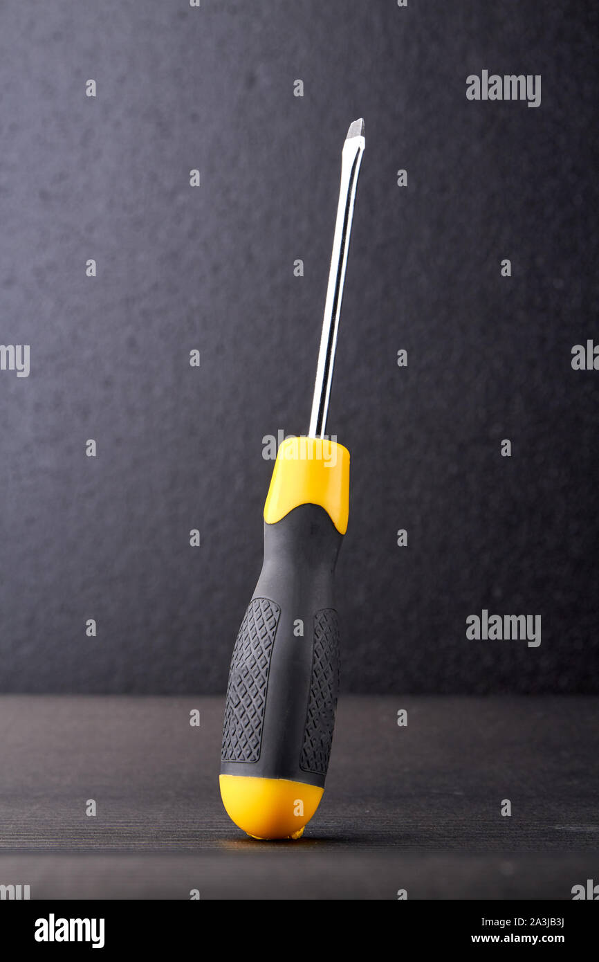 Screwdriver with rubber handle on dark background Stock Photo - Alamy