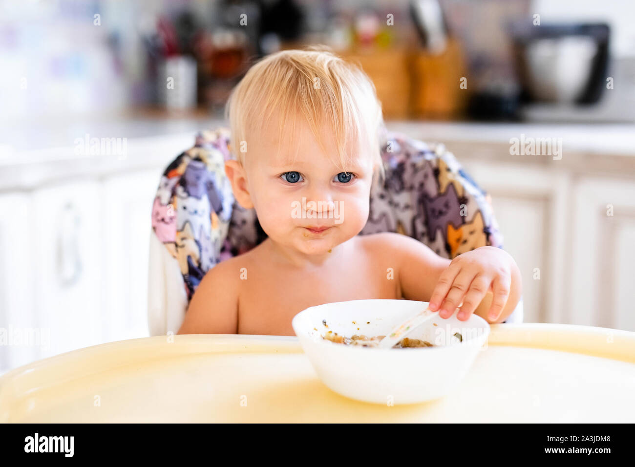 little baby at home sitting at the table and having meal Stock Photo ...