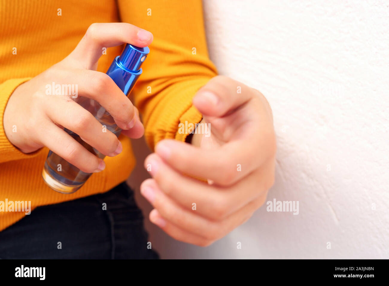 Beautiful young girl dressed in yellow, spraying perfume from a blue ...
