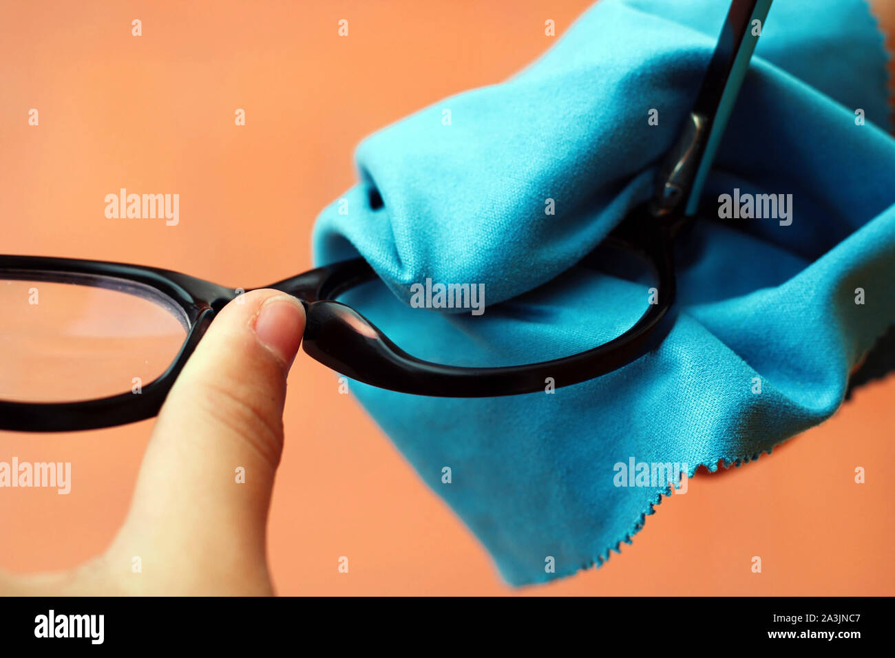 Pretty young girl cleaning her blue glasses with a blue rag. Blue ...