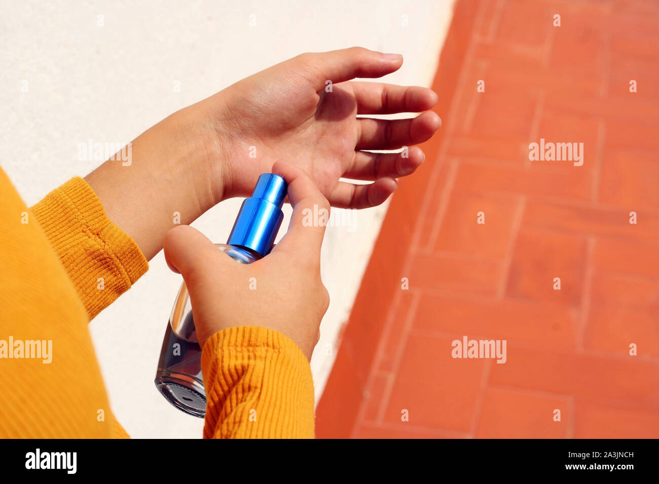 Beautiful young girl dressed in yellow, spraying perfume from a blue ...