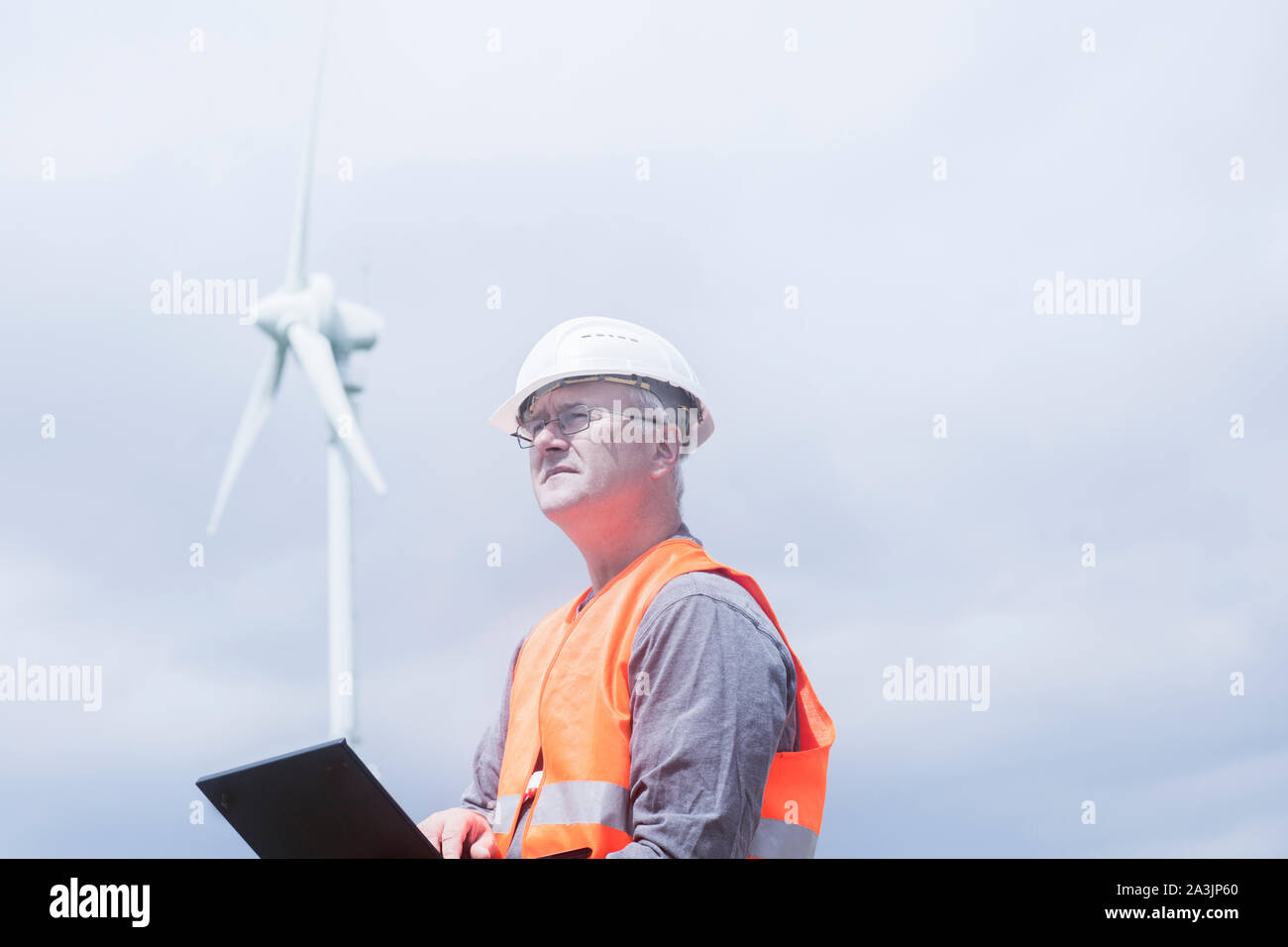older energy engineer in front of a wind turbine Stock Photo - Alamy