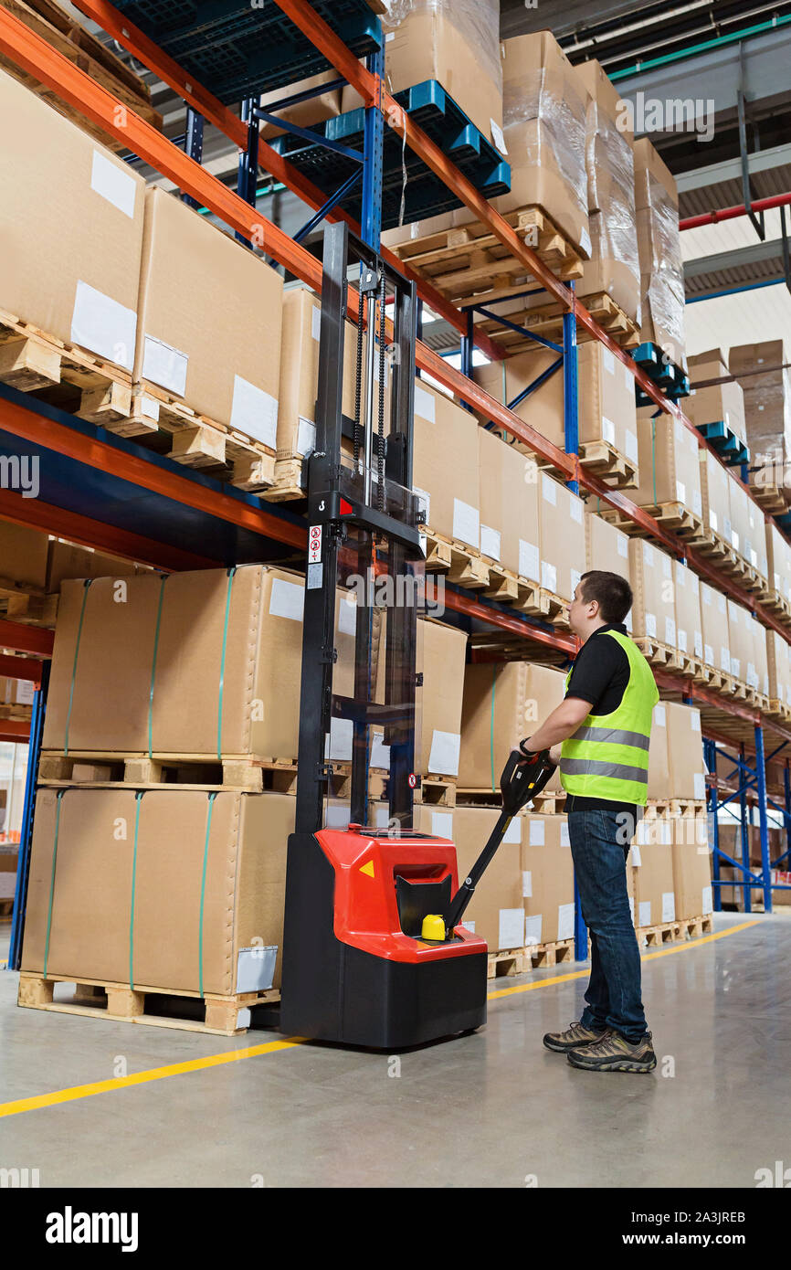 Storehouse employee in uniform working on forklift in modern automatic ...