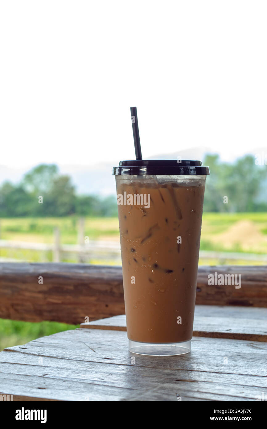 Iced coffee on the wooden floor behind a paddy field Stock Photo - Alamy