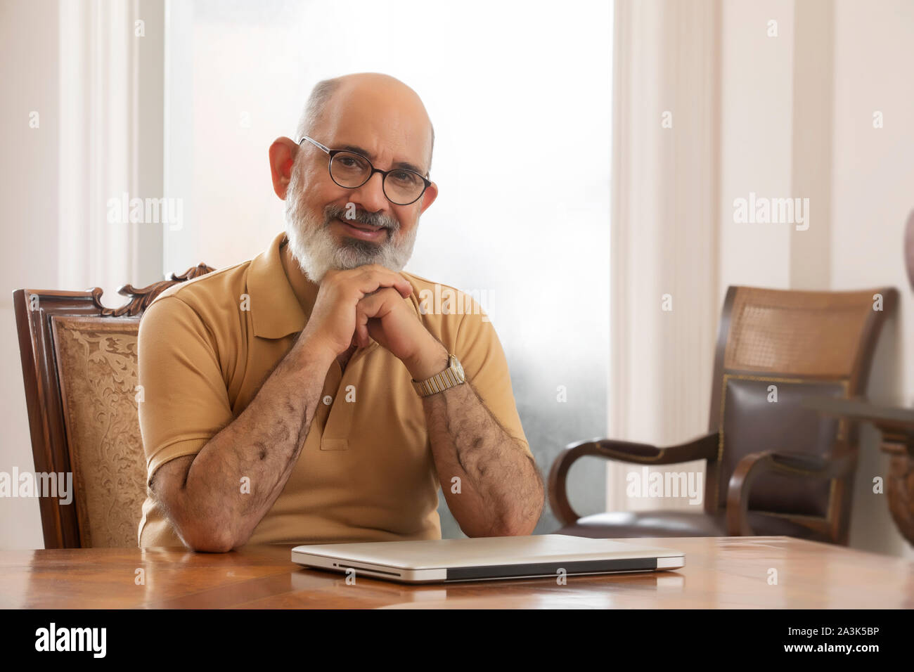 An old man smiling while sitting at the dining table. (Senior Stock ...