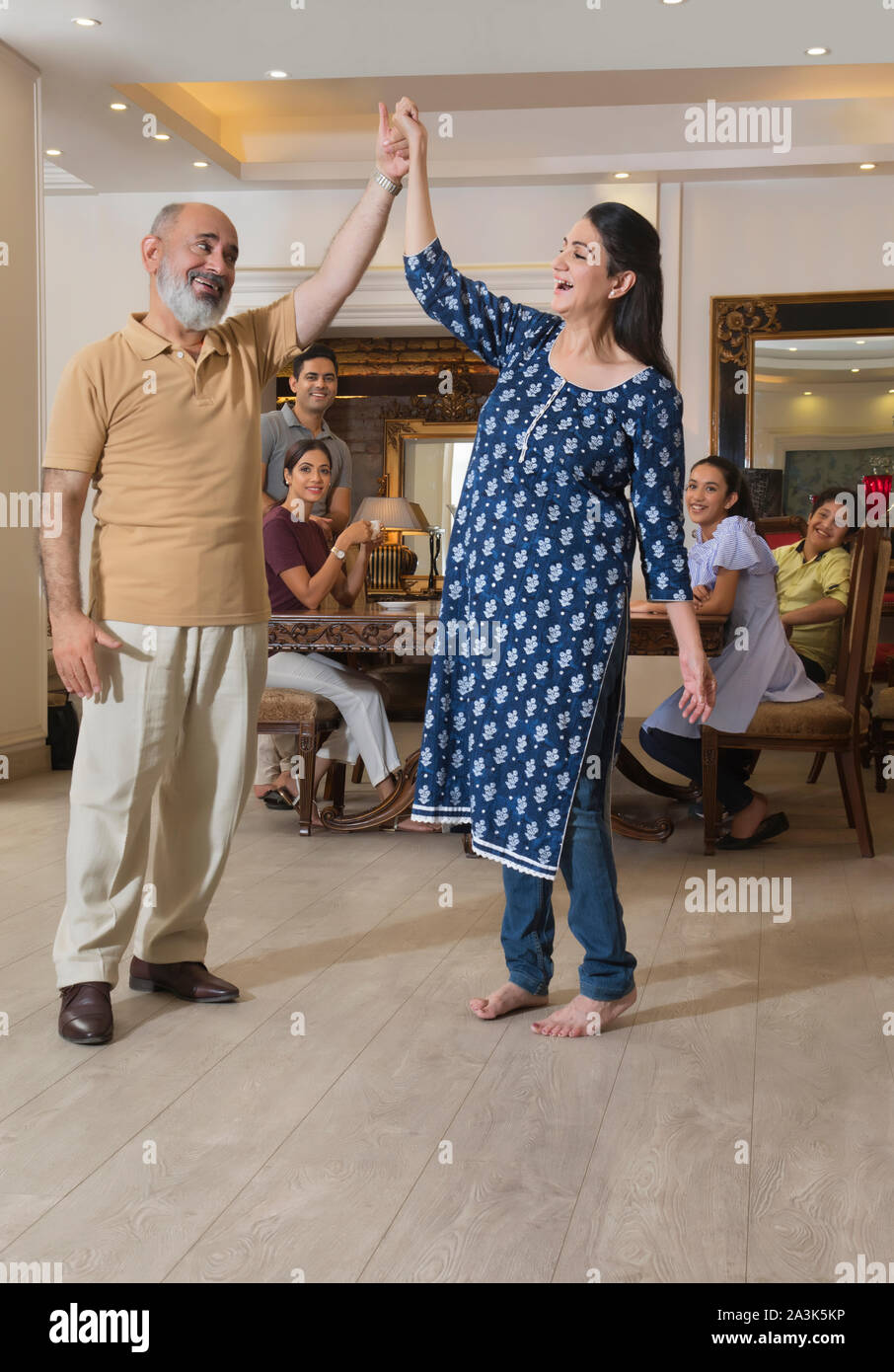 Grandparents dance in the living room in front of the family Stock ...