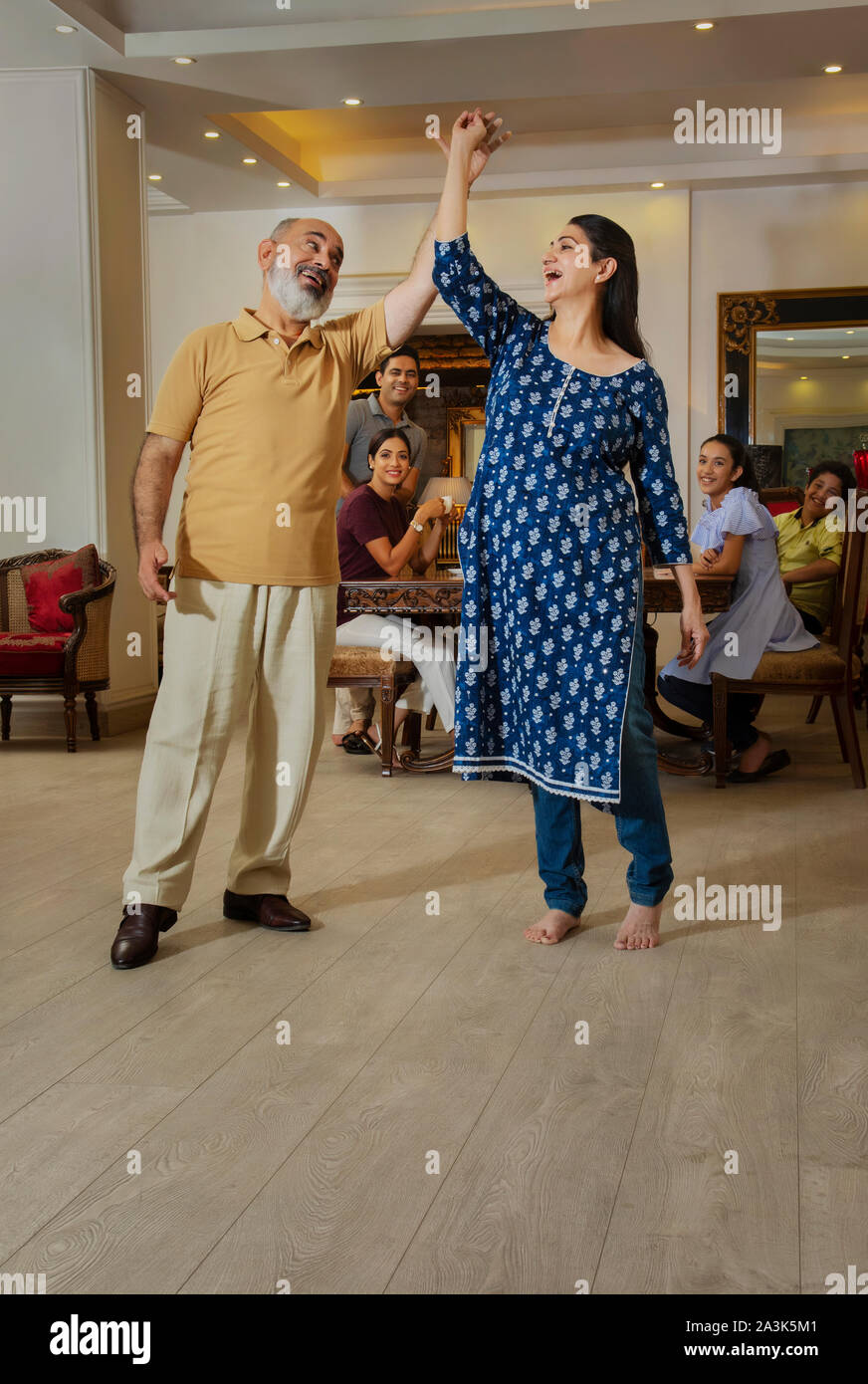 Grandparents dance in the living room in front of the family Stock ...