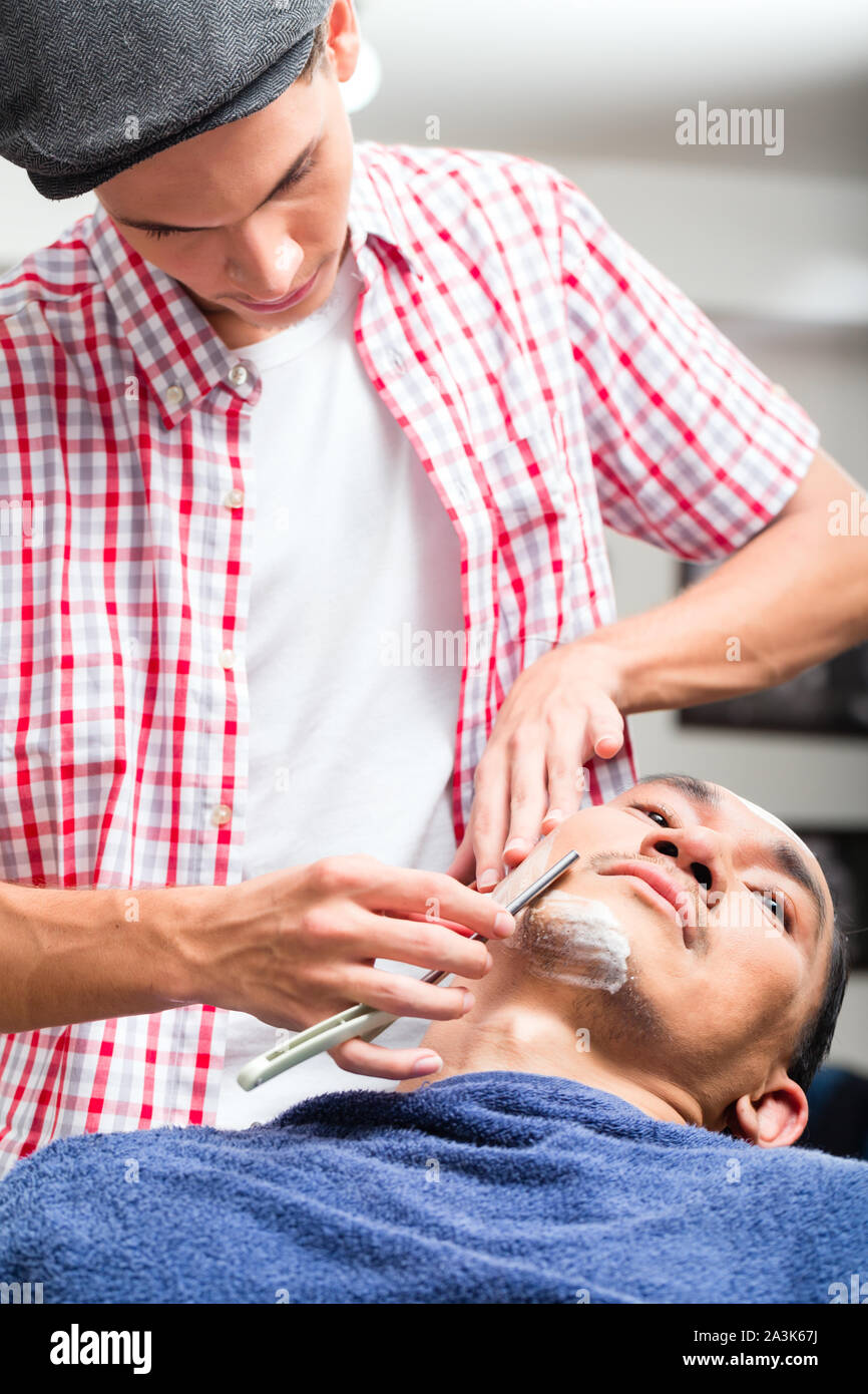 Hairdresser shaving with straight razor Stock Photo - Alamy