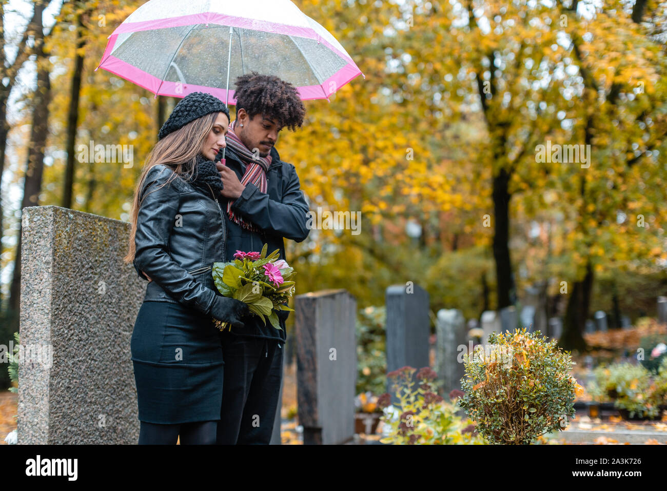 Couple in grief on a cemetery in fall Stock Photo - Alamy