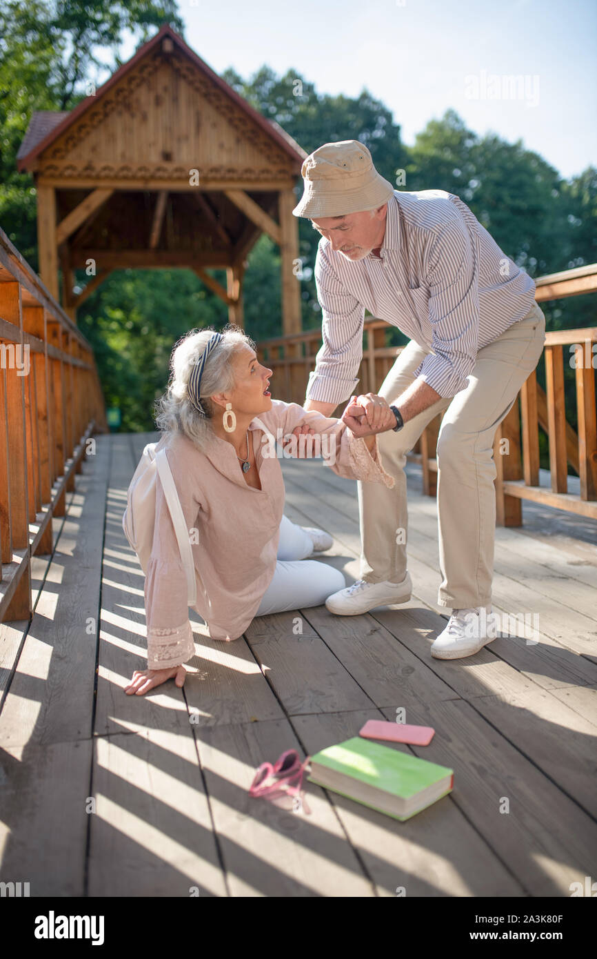 Husband helping his wife to stand up after falling on the bridge Stock ...