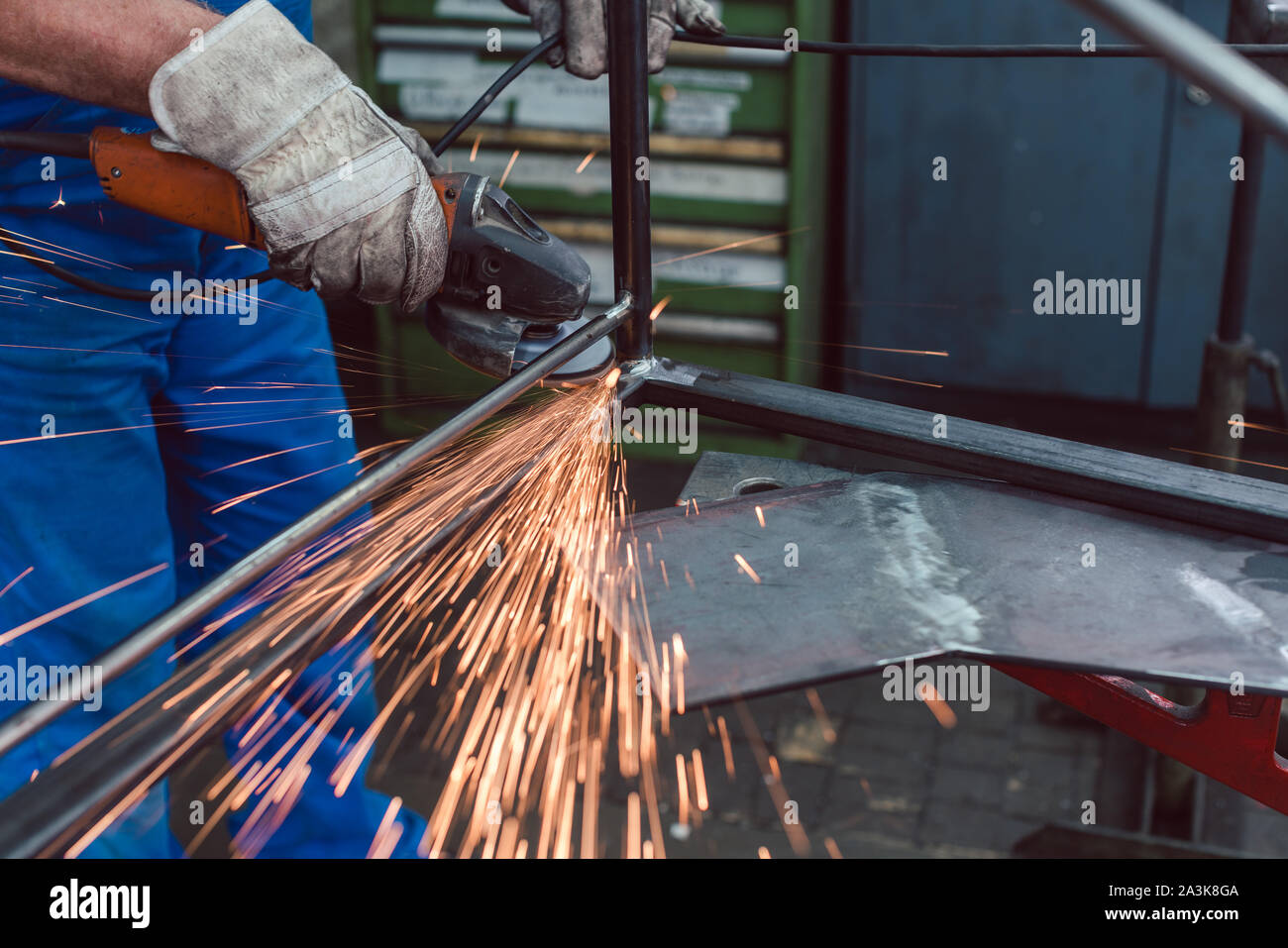 Worker in metal factory grinding workpiece with sparks flying Stock ...