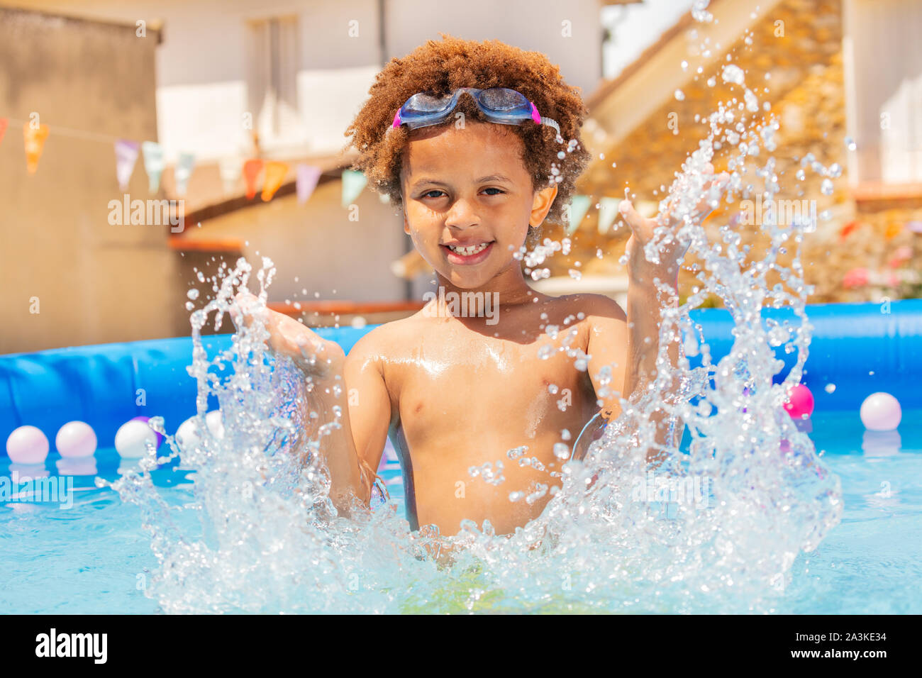 Cute curly boy splash water in small swimming pool Stock Photo - Alamy