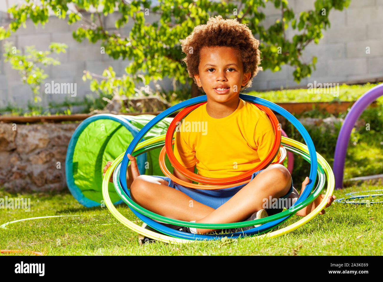 Cute curly boy portrait with color hula hoop rings Stock Photo - Alamy