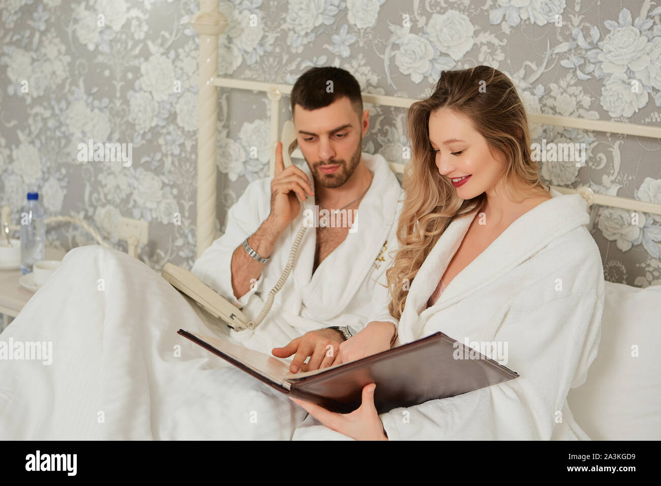 Couple with menu calling room service for food from hotel room Stock ...