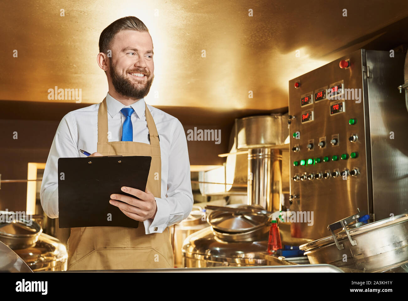 Handsome, cheerful brewery expert inspecting process of brewing beer ...