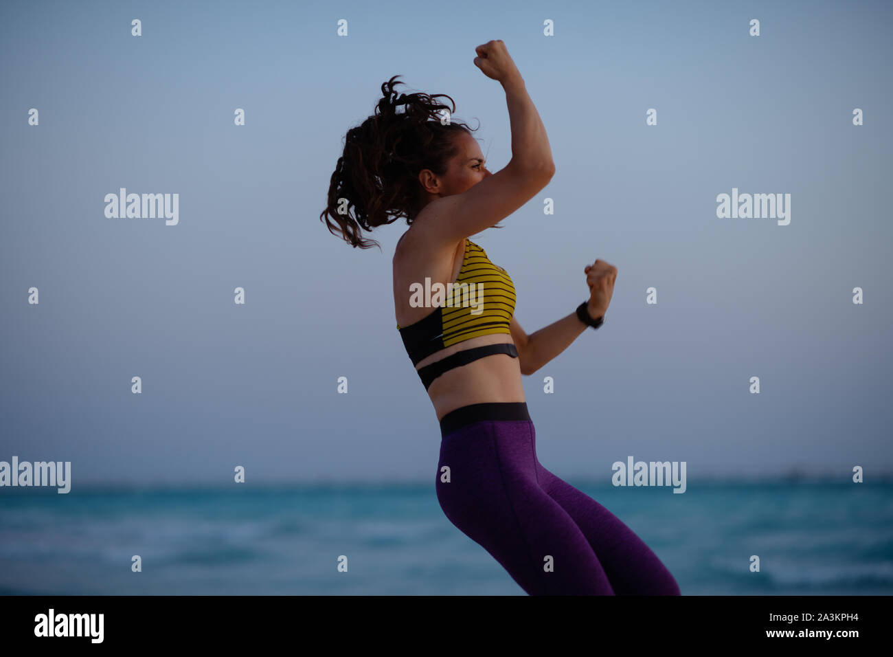 fitness woman in sport style clothes on the ocean coast in the evening ...