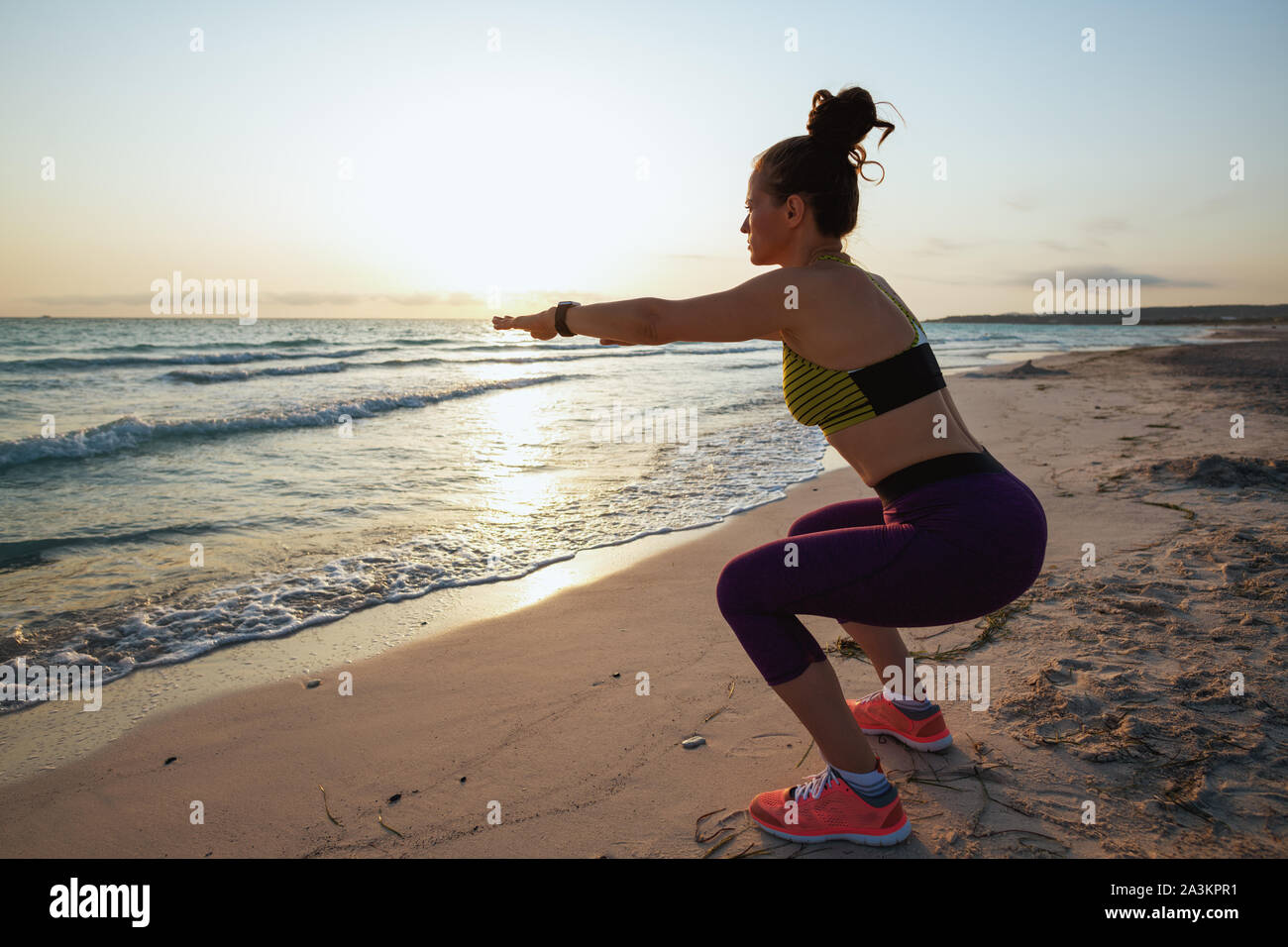 healthy woman in sport clothes on the seashore in the evening doing ...