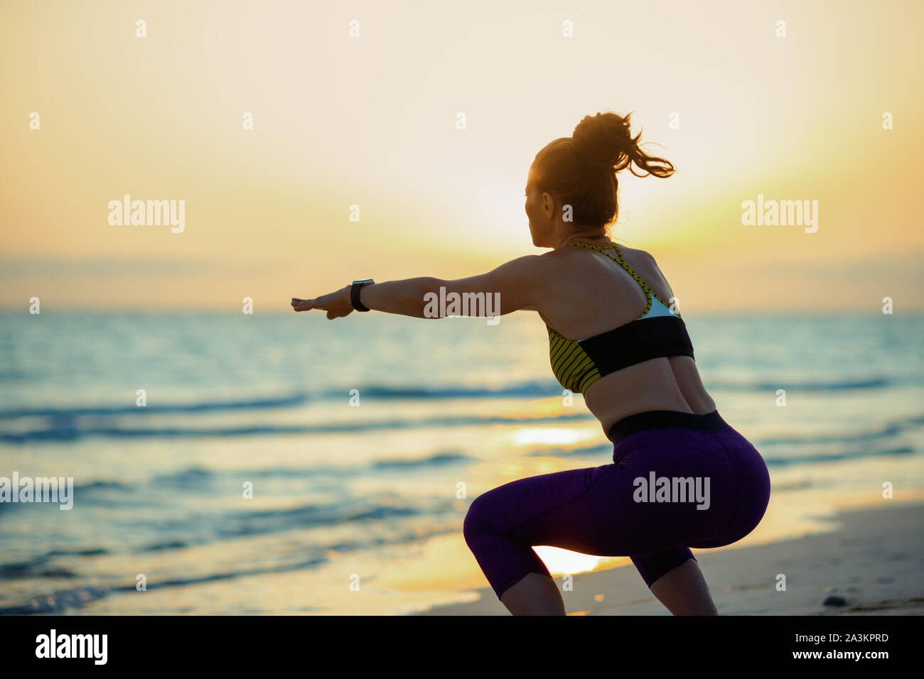 Seen from behind young sports woman in fitness clothes on the ocean ...