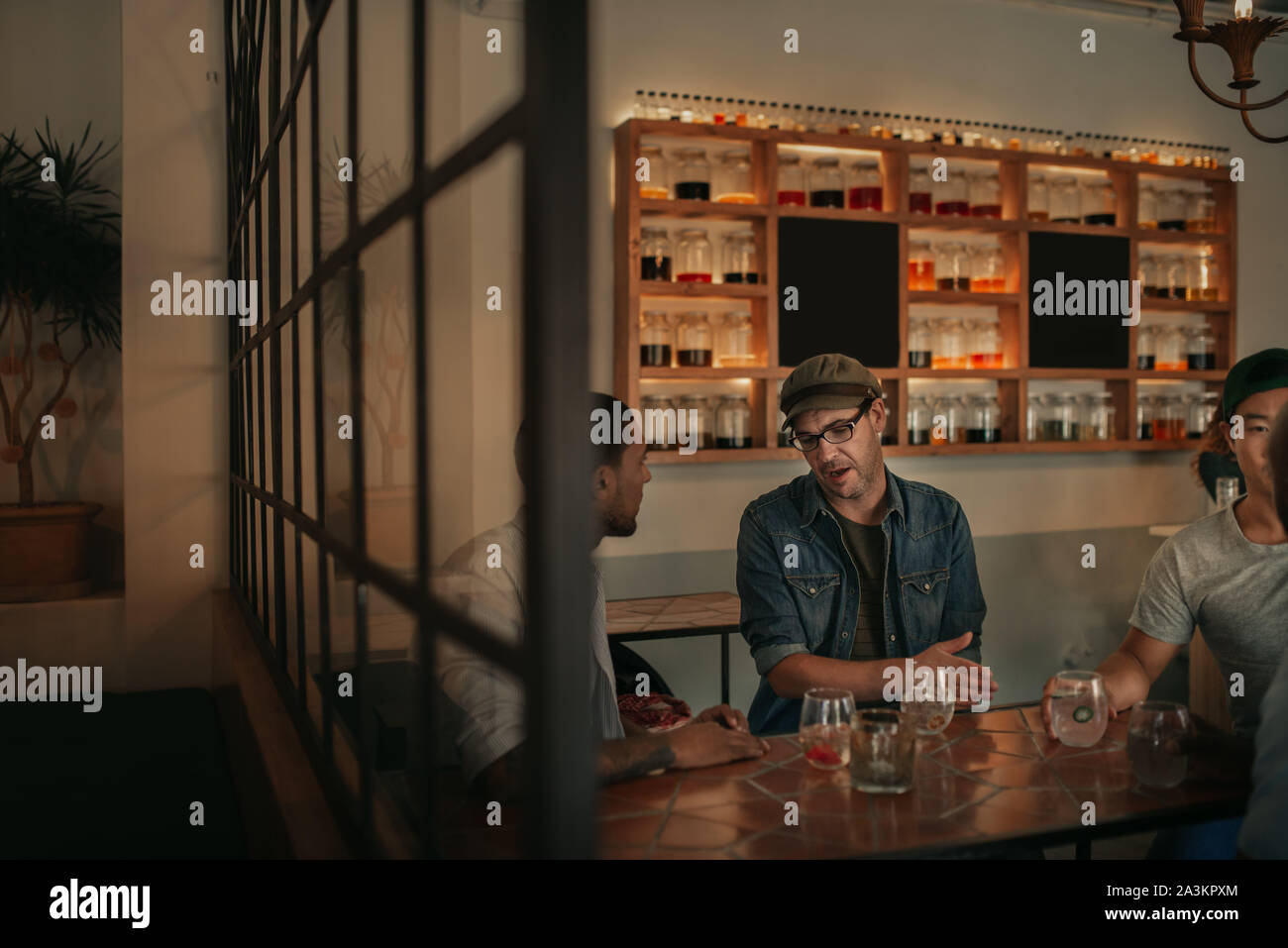 Friends talking together over drinks in a bar at night Stock Photo - Alamy