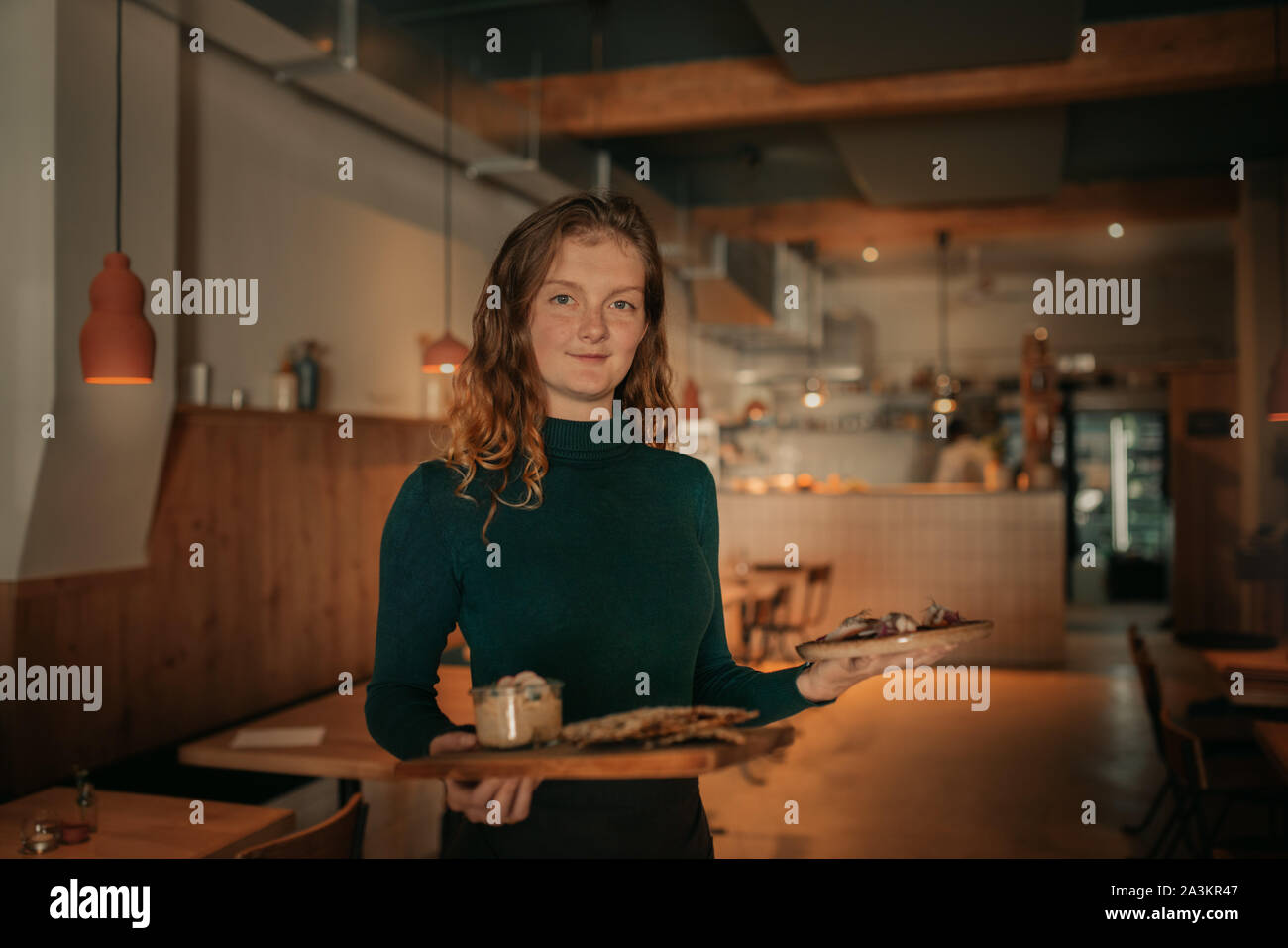 Waitress carrying orders of food in a bistro at night Stock Photo - Alamy