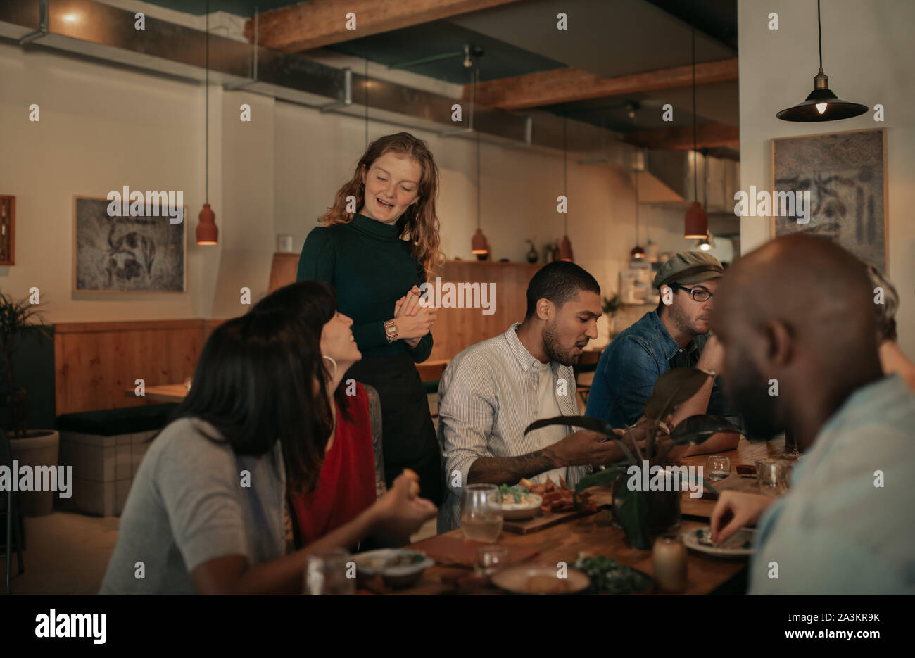 Friendly bistro waitress talking with a table of smiling customers ...