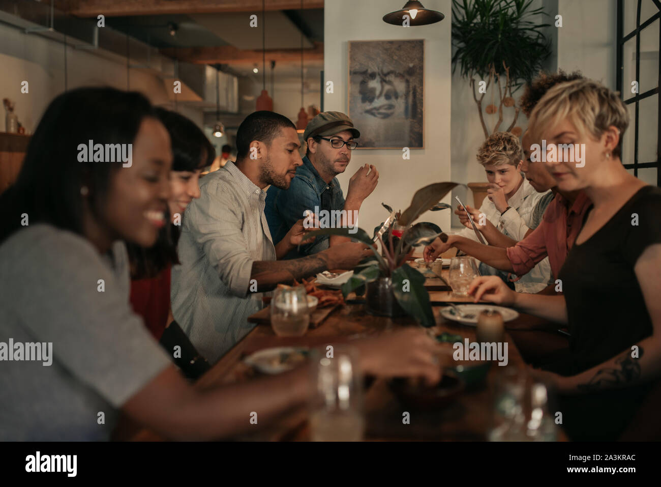 Diverse friends talking over a bistro dinner at night Stock Photo - Alamy