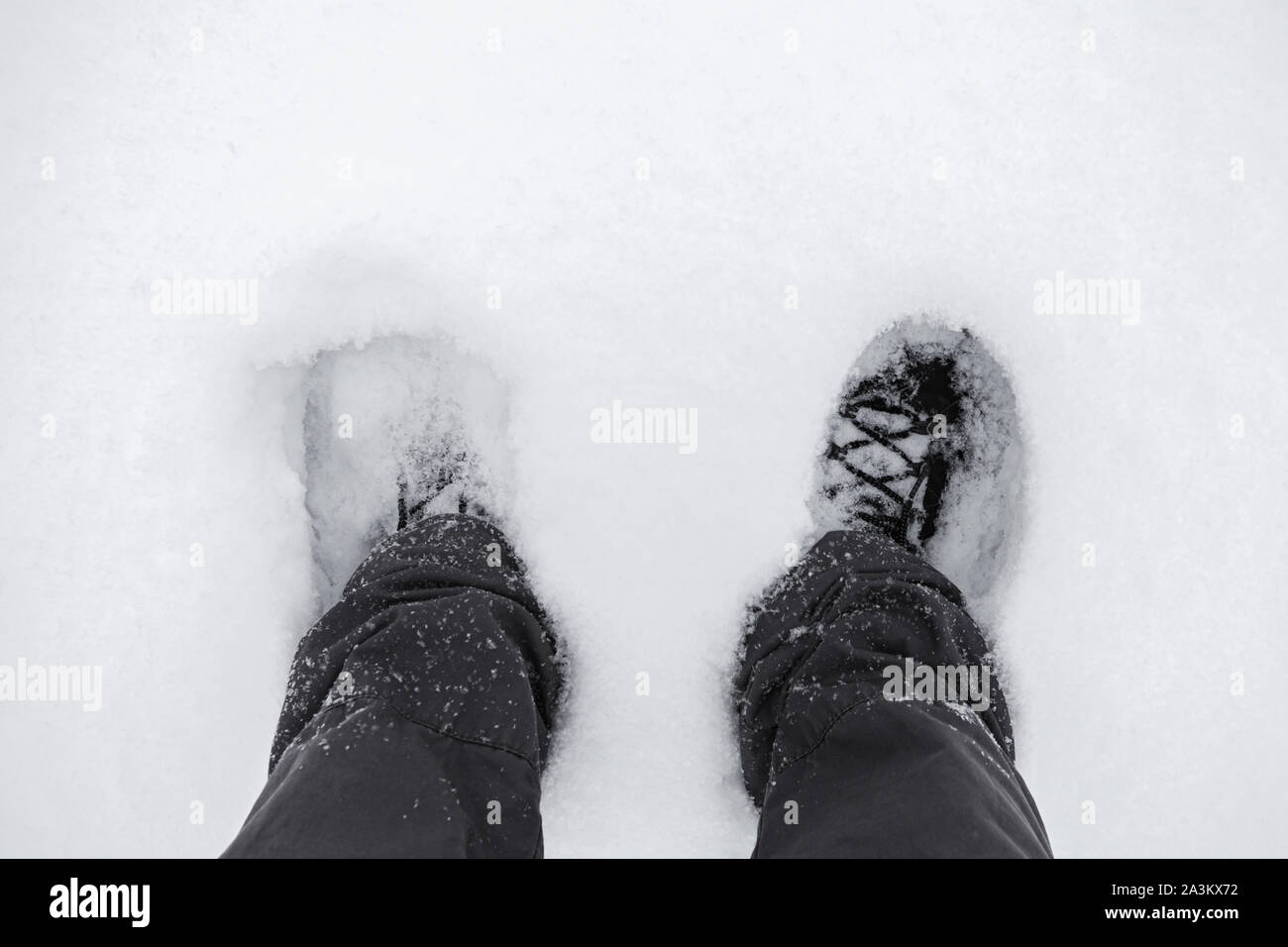 Male feet in black shoes standing in deep snow, first person top view ...