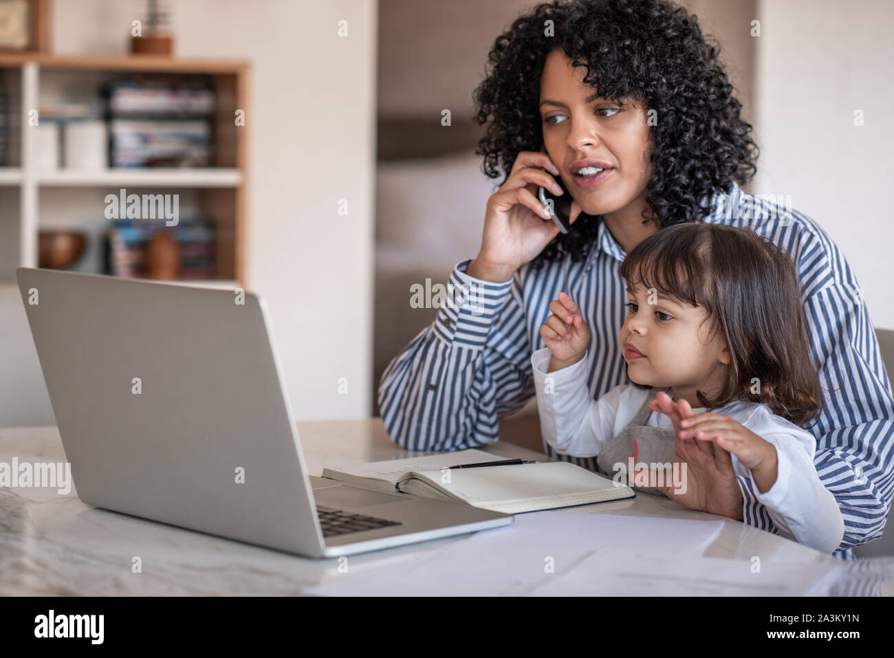 Busy mother and entrepreneur working at home with her daughter Stock ...
