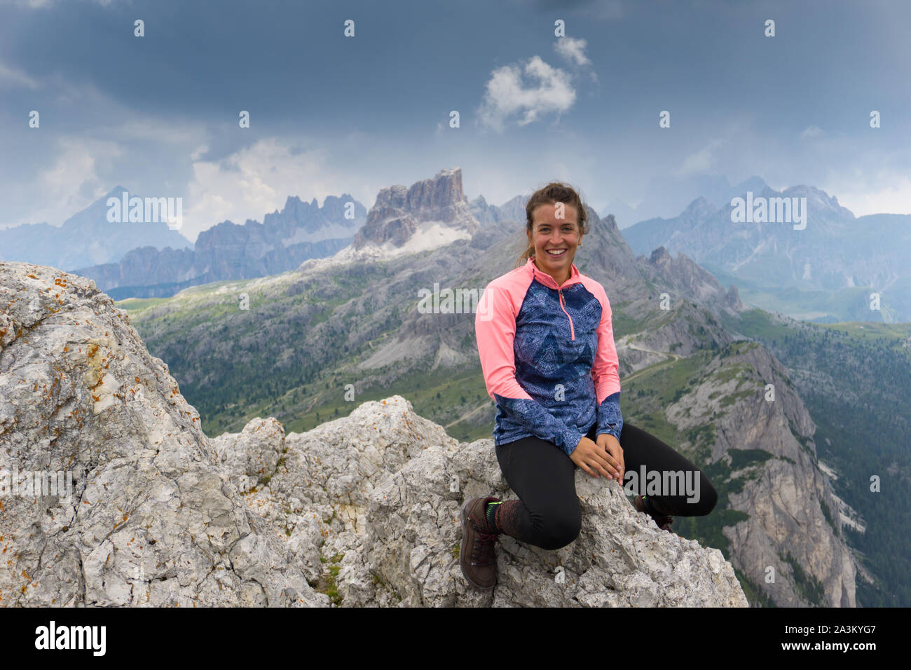 An attractive brunette mountain climber sitting on a mountain peak and ...