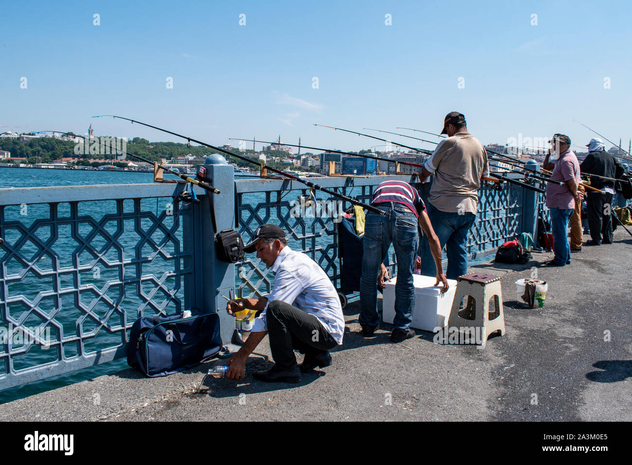 Istanbul: skyline of the city and local fishermen with their fishing ...