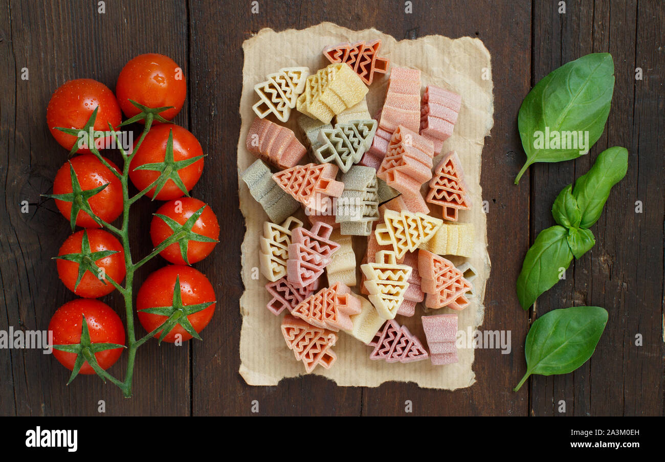 Tricolor fir tree shaped pasta, tomatoes and basil on wood Stock Photo ...