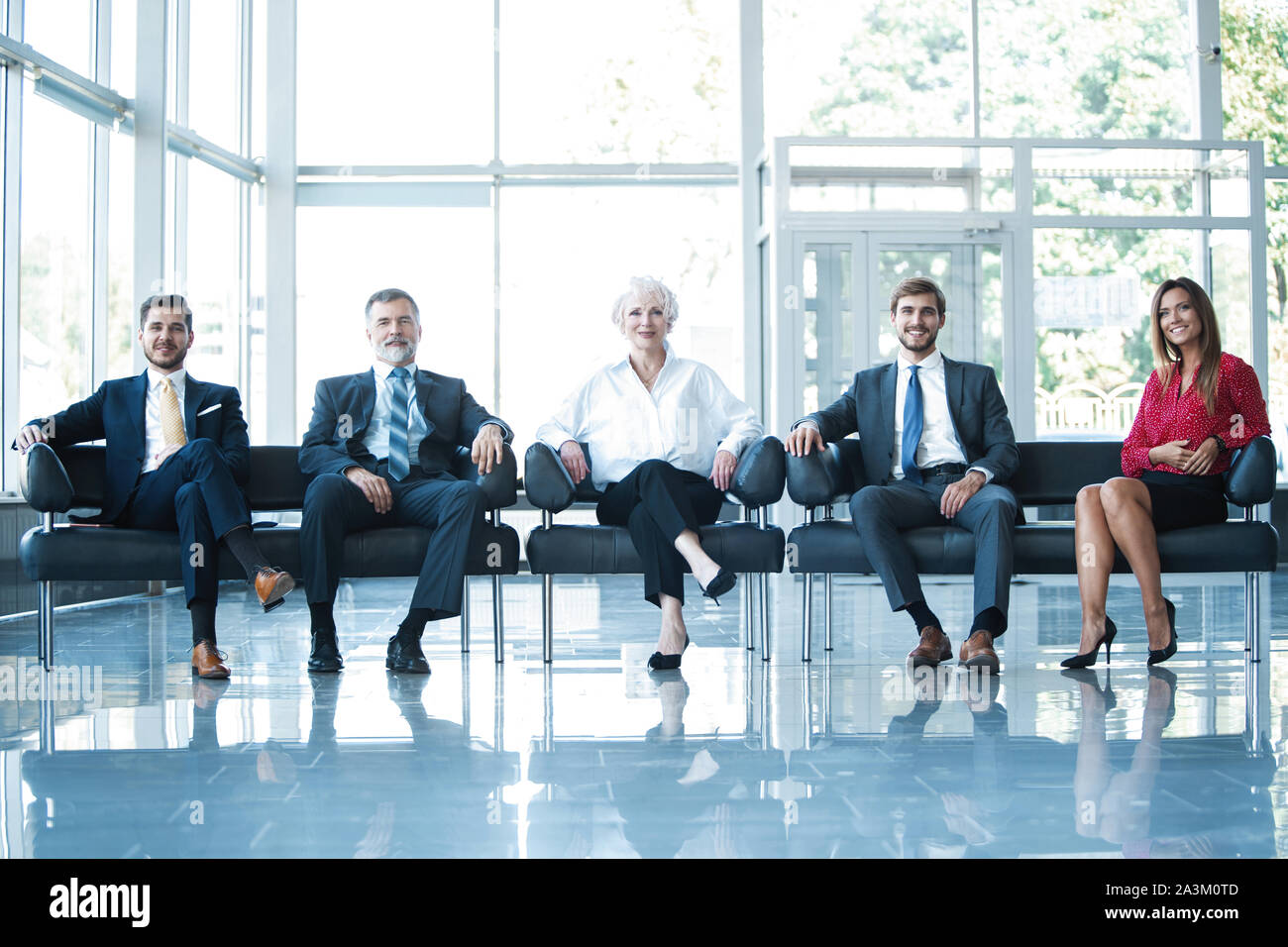 Confident business team sitting on chairs in a row Stock Photo - Alamy