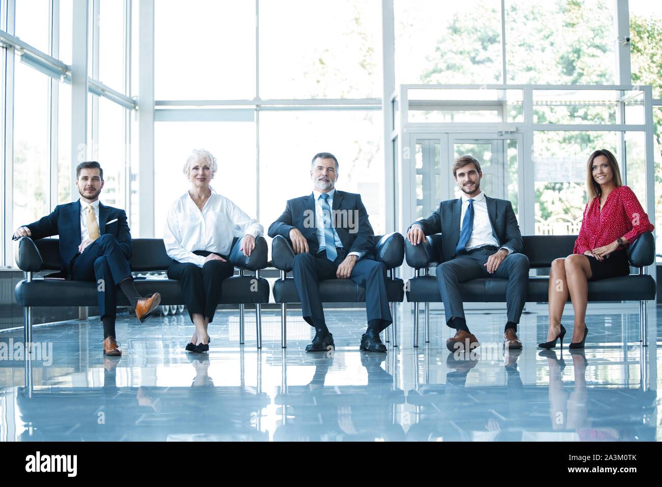 Confident business team sitting on chairs in a row Stock Photo - Alamy
