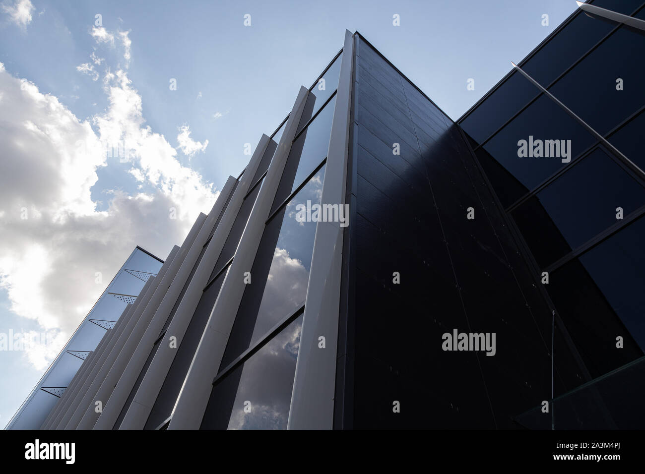 Bottom view of new and modern building with glass walls reflecting sky ...
