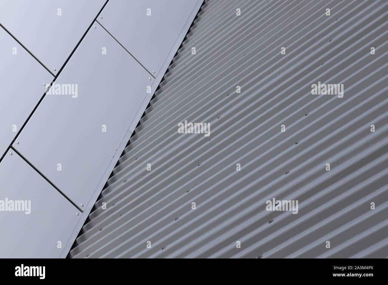 Angular view of corner of building - junction of grey smooth tiled wall ...