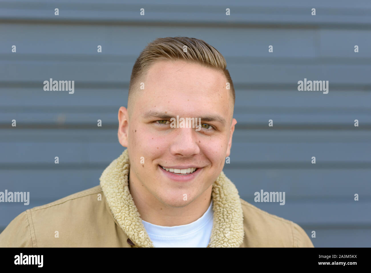 Attractive friendly young man in his twenties looking at the camera ...