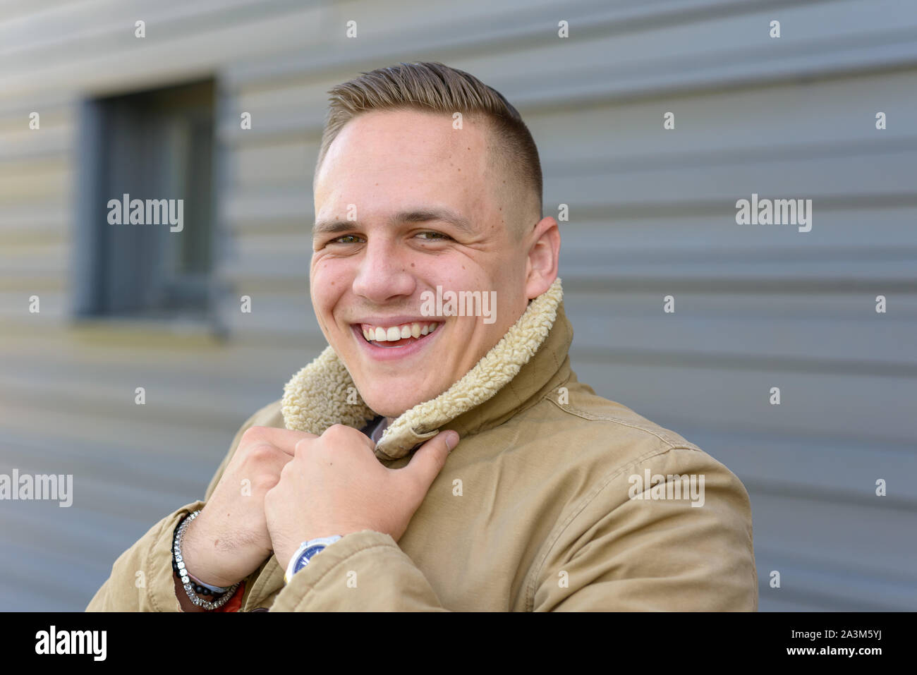 Happy young man with a charismatic smile standing outdoors on a cold ...