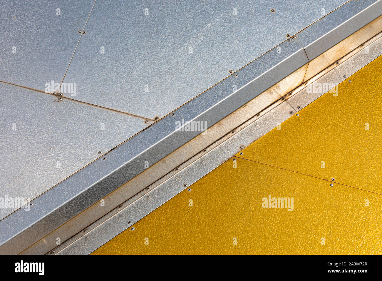 Diagonal joint of two colourful, yellow and gray aluminium steel panels ...