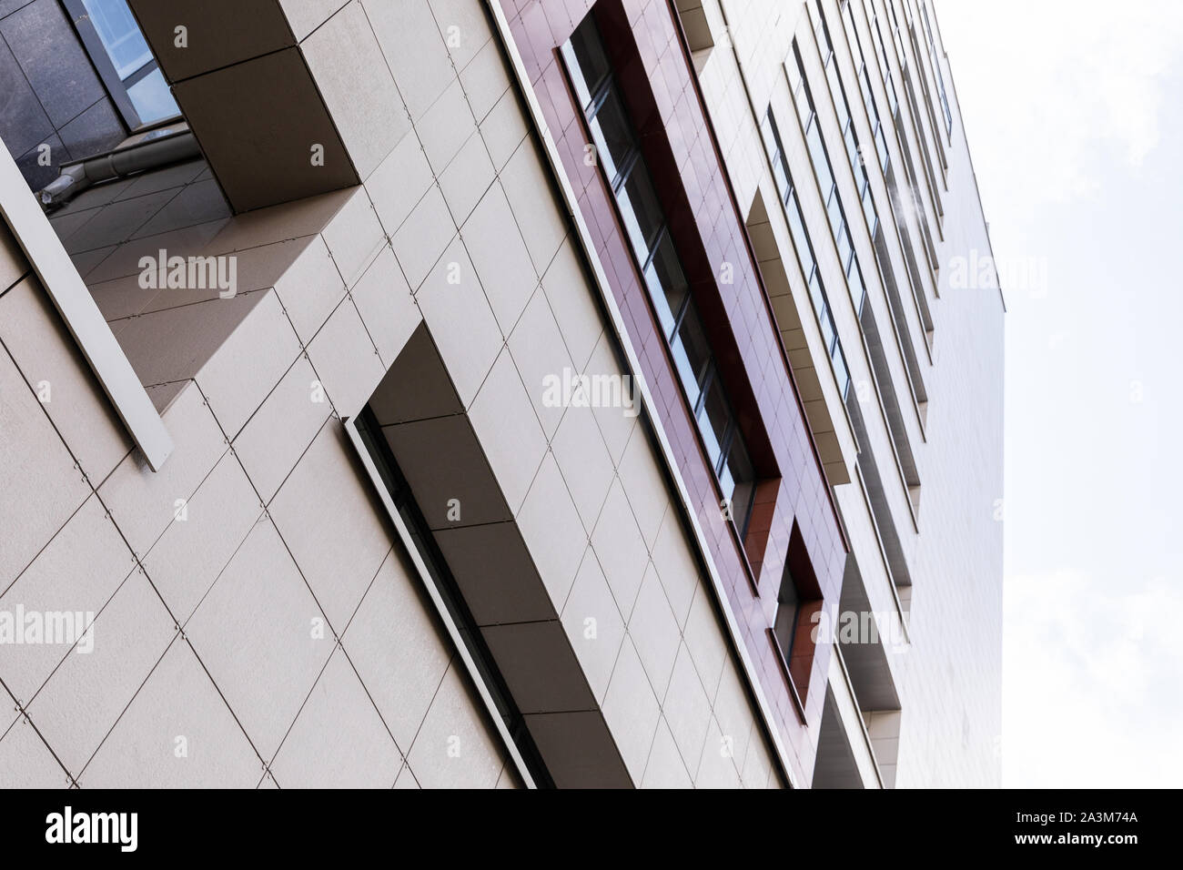 Ground view of tall building facade, fenced with beige square tiles ...