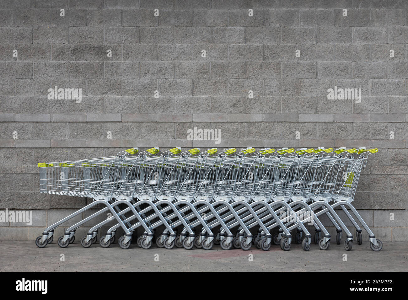 Many empty shopping trolleys with yellow handle standing in a row in ...