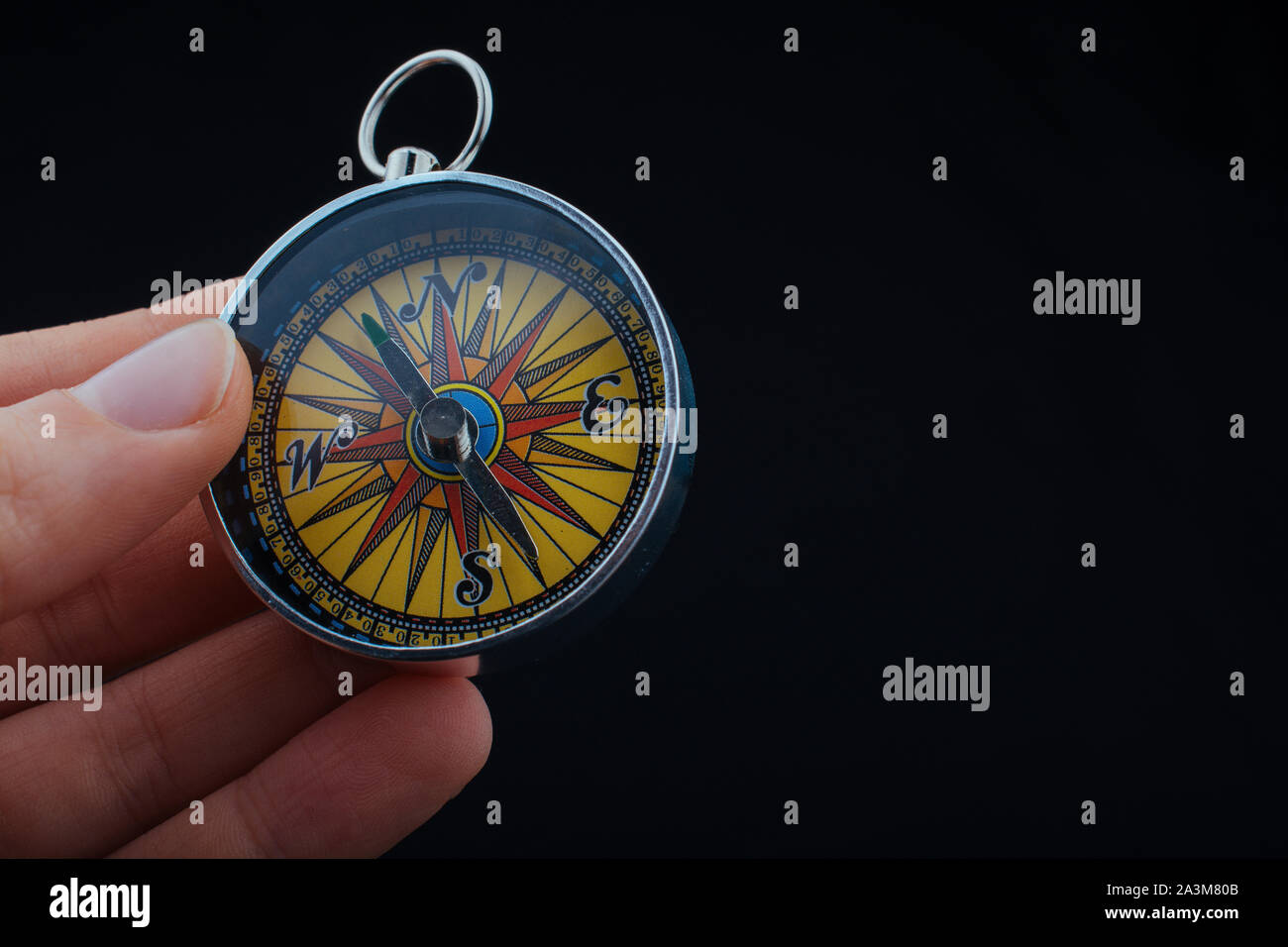 Hand is holding a magnetic compass on black background Stock Photo - Alamy
