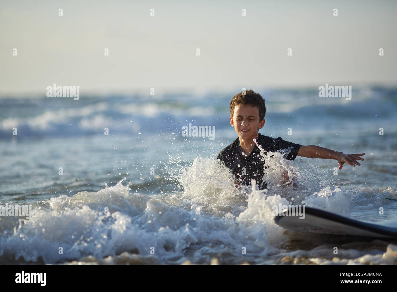 boy falls from a surfboard into the water, riding lessons on the waves ...
