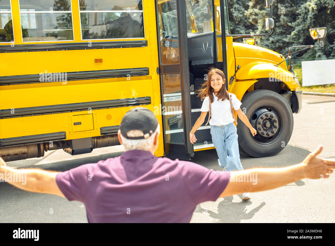Father meeting daughter coming out of school bus hands aside cheerful ...