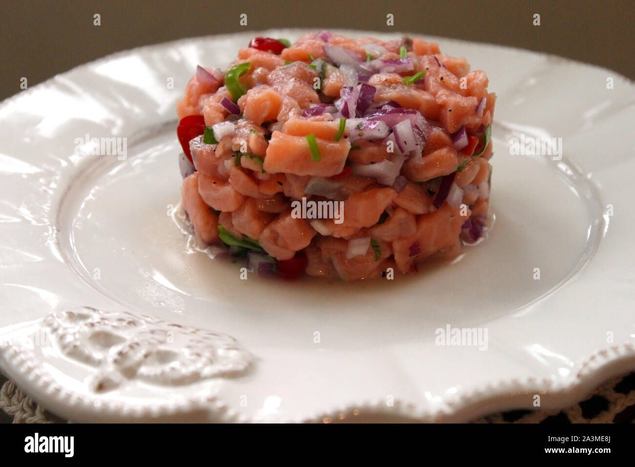 Salmon fish ceviche serving in a cooking ring close up on white plate ...