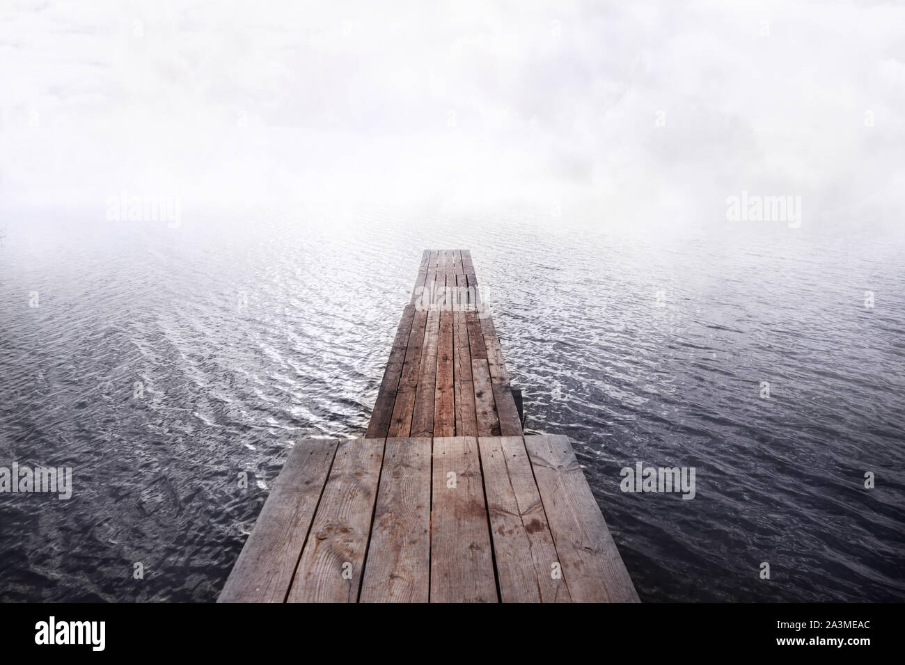 front view of wooden pier going into the water and fog, depression and ...