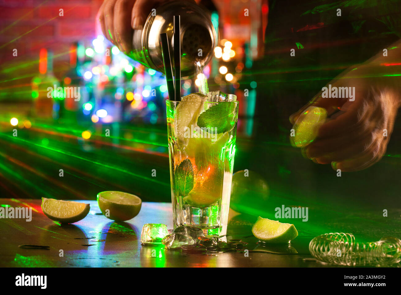 Closeup of barman making mojito cocktail on a bar lights background ...