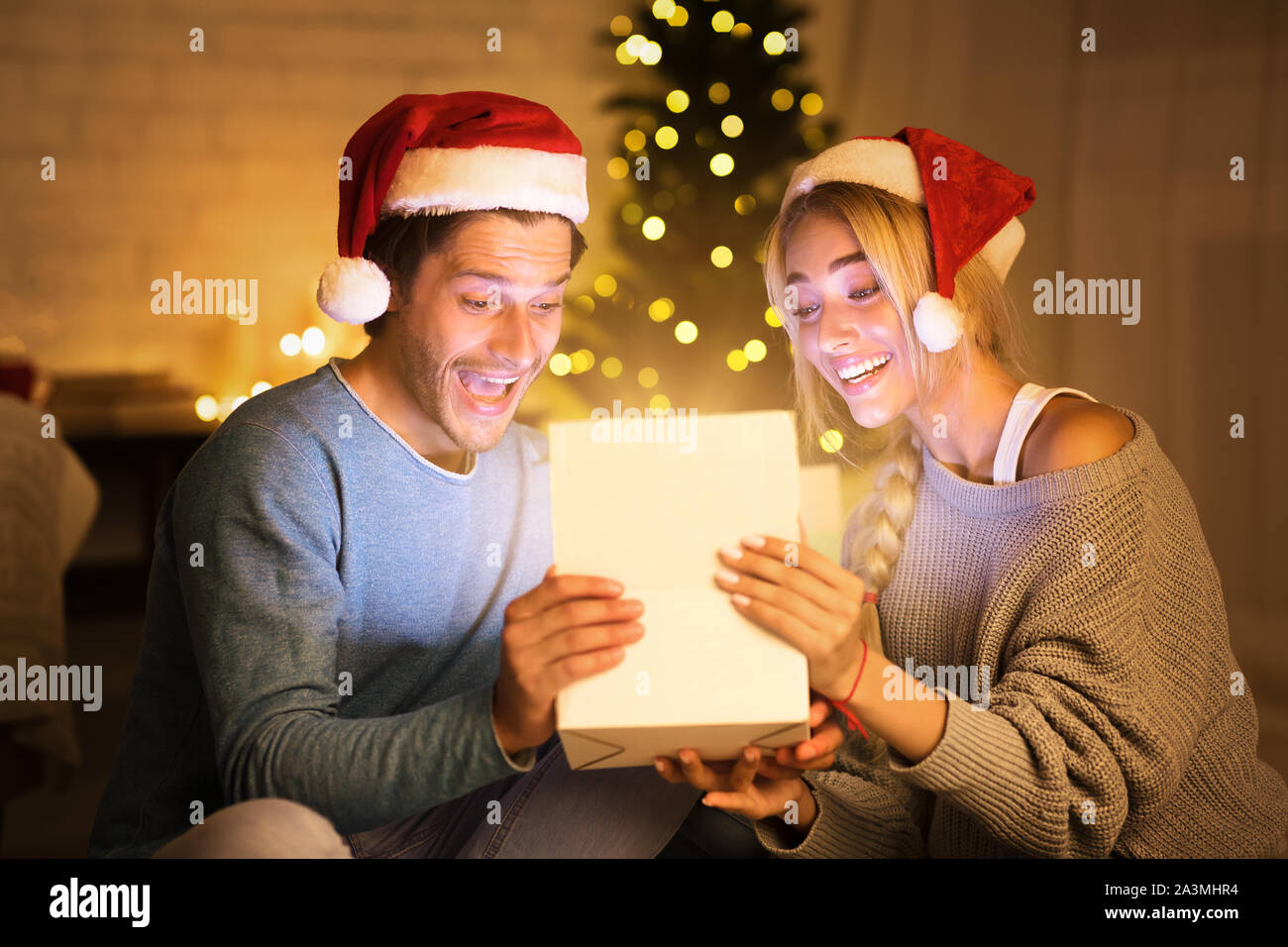 Magical surprise. Couple opening xmas gift box Stock Photo - Alamy