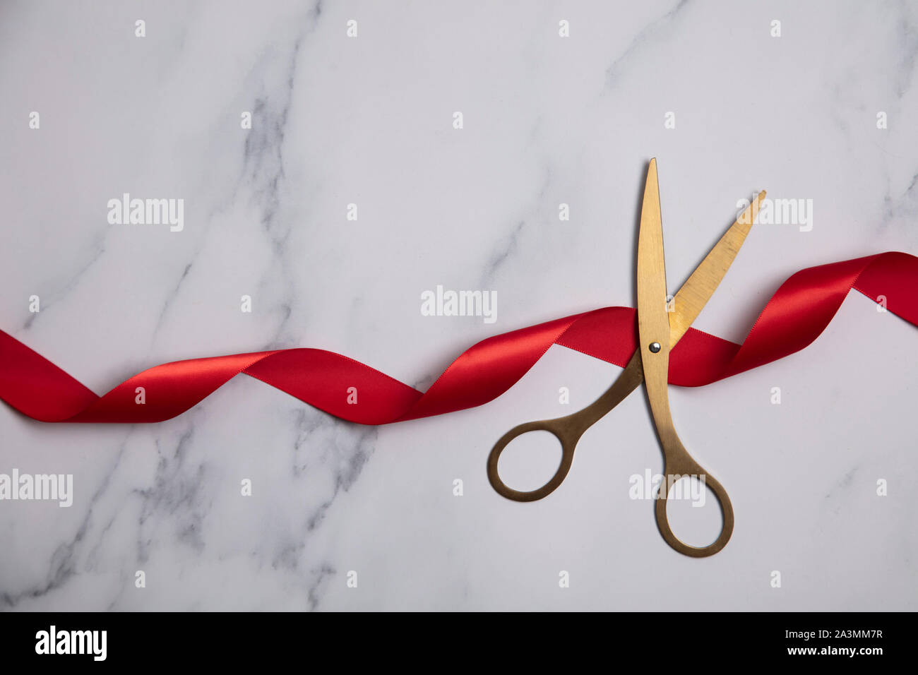 Grand opening background. Gold scissors with red ribbon on a marble ...