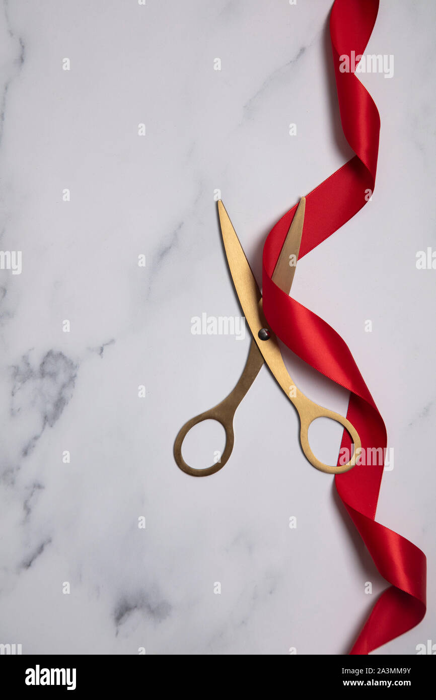 Grand opening background. Gold scissors with red ribbon on a marble ...