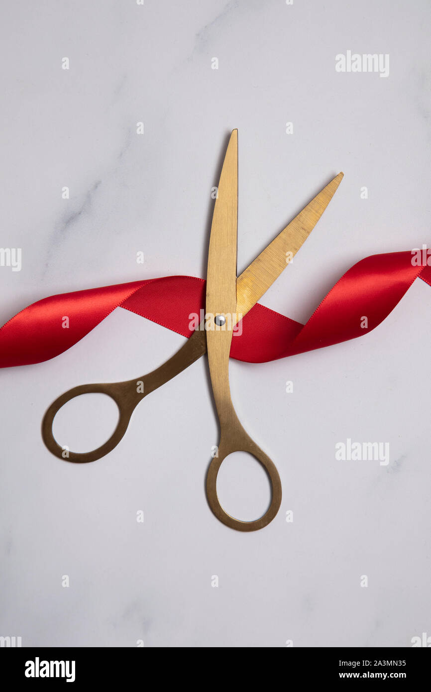 Grand opening background. Gold scissors with red ribbon on a marble ...